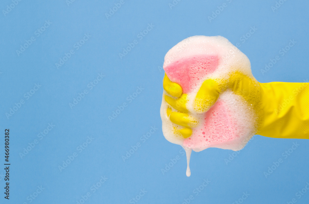 Poster Rubber gloved hand holding soapy kitchen sponge with copy space ...