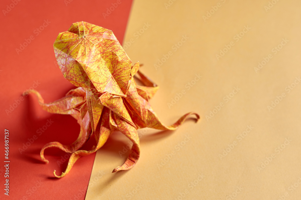 Origami octopus model on a yellow and orange background. Origami figure ...