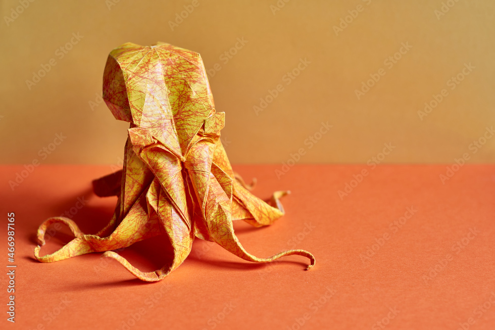 Origami octopus model on a yellow and orange background. Origami figure ...