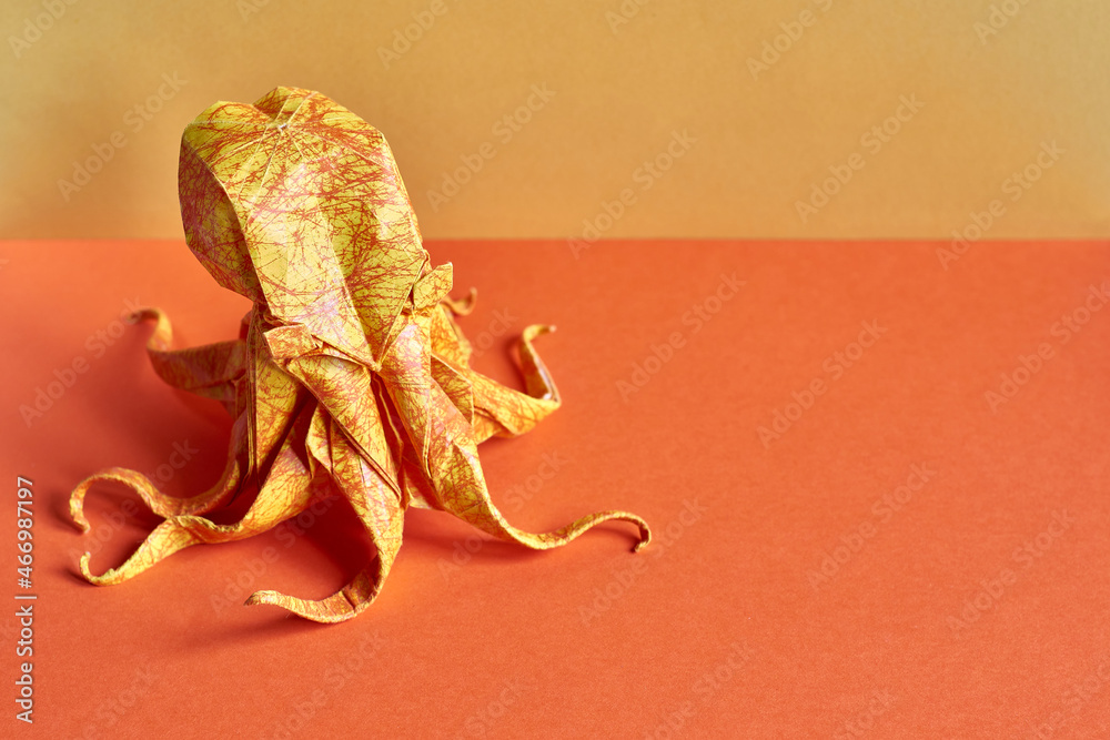 Origami octopus model on a yellow and orange background. Origami figure ...