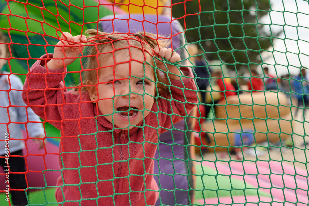 Little girl laughs as she grabs behind a playground net Stock Photo ...