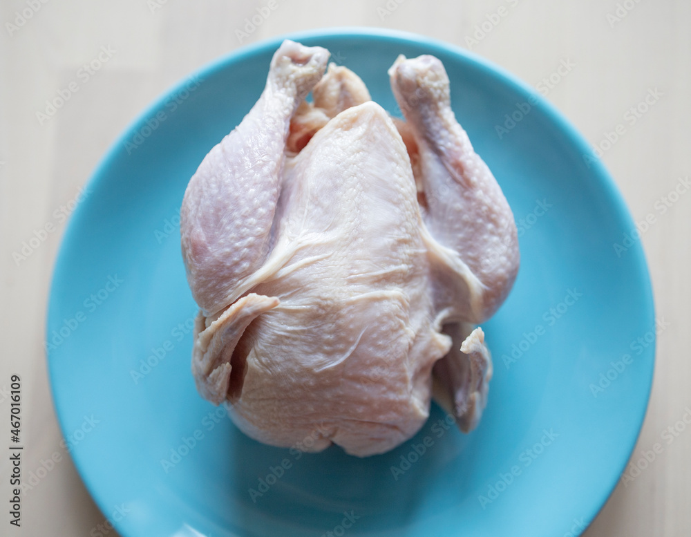 broiler chicken carcass, with skin, on a plate, on a light background ...