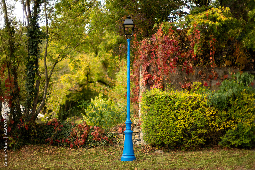 Blue light pole with colorful fall foliage background and brick wall in ...