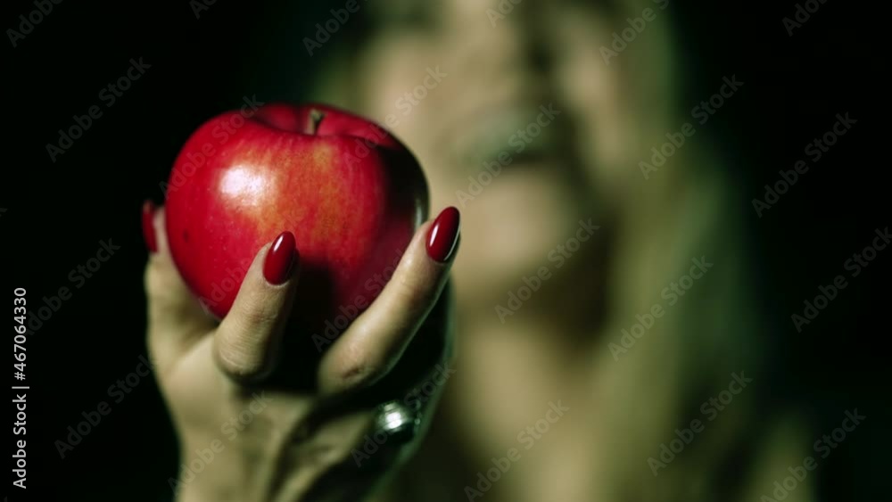 Woman as witch with an evil grin, laugh in black offers red apple as ...