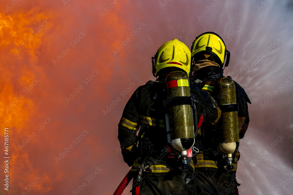firefighters wearing fire fighter suit for safety and using twirl water ...