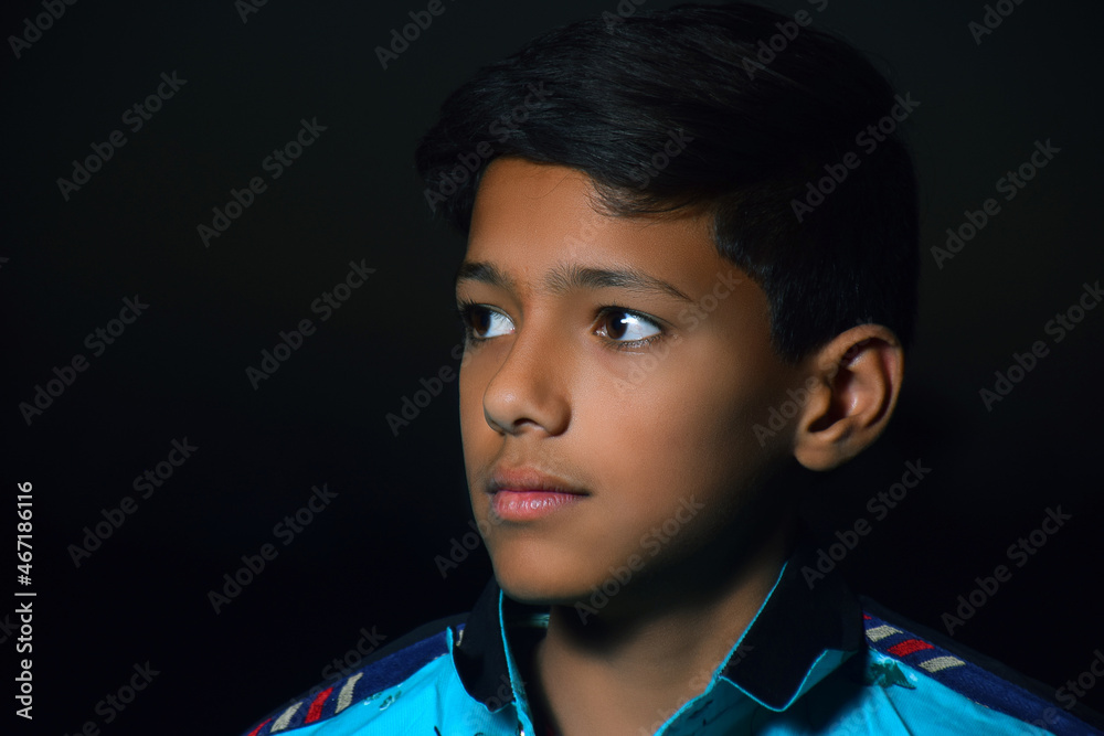Side view portrait of a cute Asian boy looking against black background ...