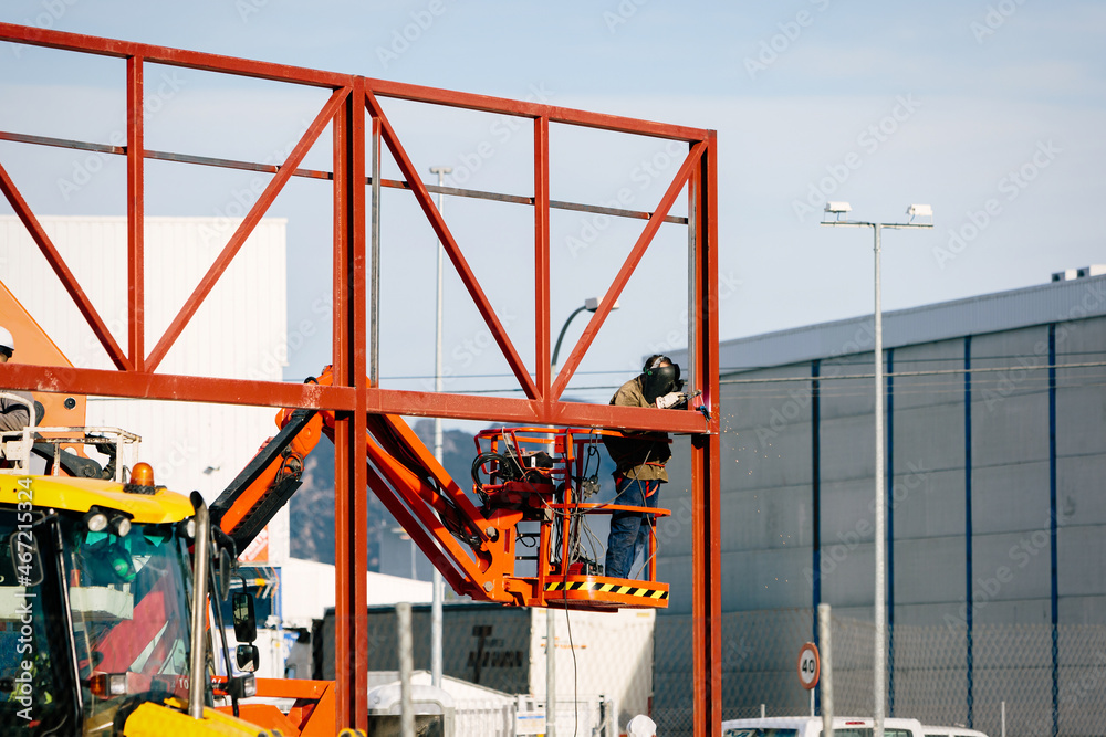 Man welding a billboard frame above a building Stock Photo | Adobe Stock