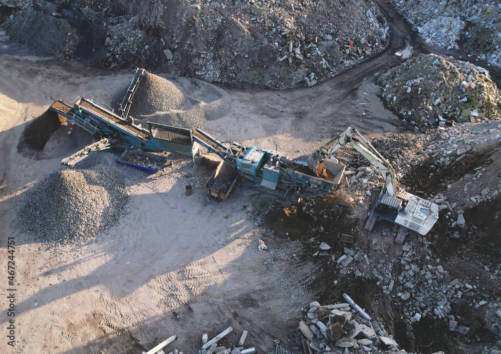 Excavator at landfill the load concrete waste in a mobile jaw crusher ...