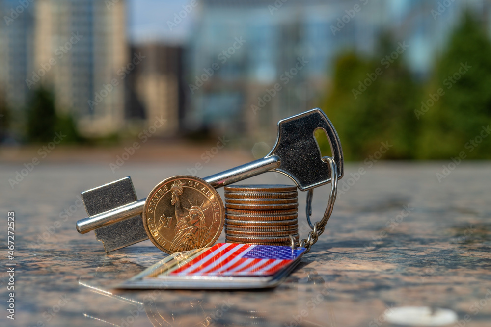 Key and column of american coins on the background of modern buildings ...
