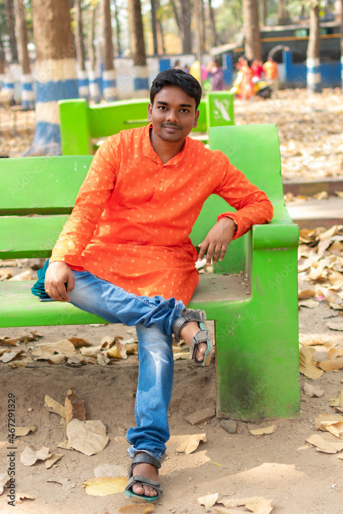 Portrait of a bengali man sitting with his legs crossed and smiling in ...
