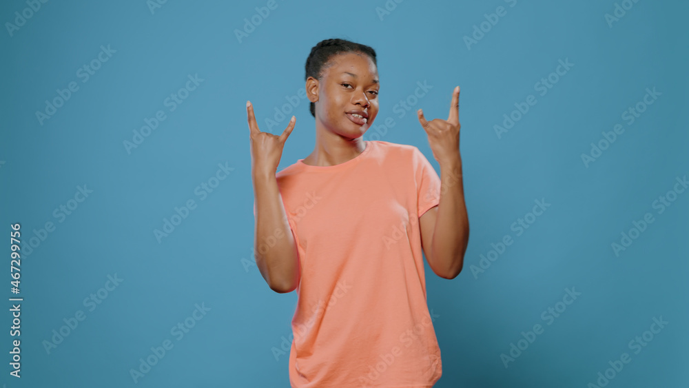 Playful person showing rock gesture with hands at camera. Young woman ...