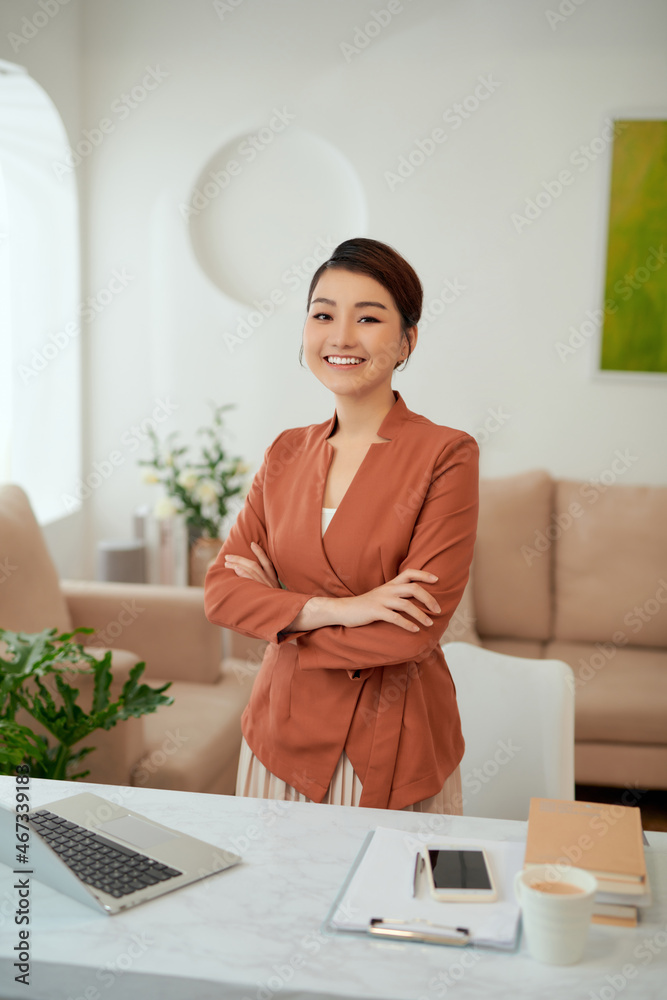 Beautiful girl stands in front of the computer in pose with her arms ...