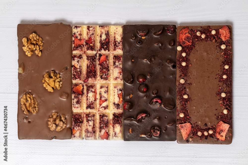 Different kinds fof chocolate bars laying down in a row on wooden white ...