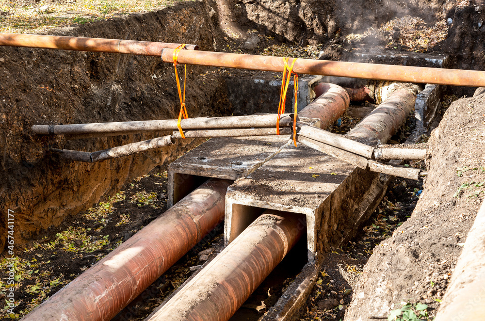 Construction works on large iron pipes at a depth of excavated trench ...