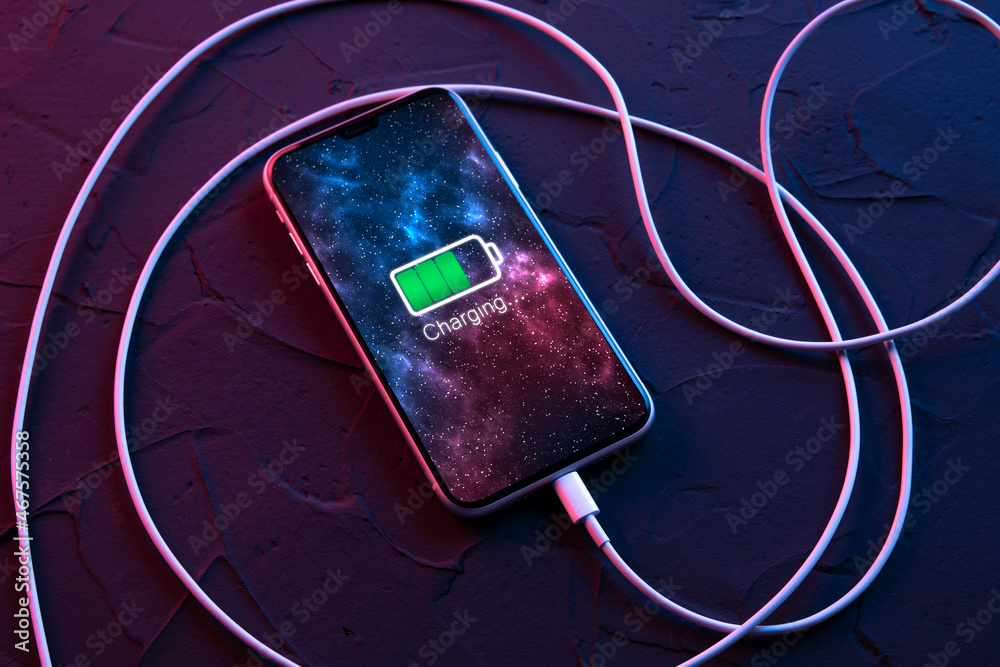 Mobile smart phone on wireless charging device on dark neon red and ...