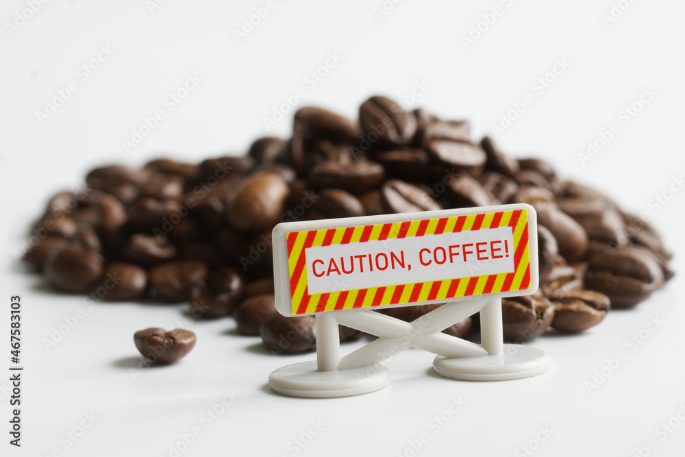 Caution coffee warning sign next to many roasted coffee beans. Concept ...