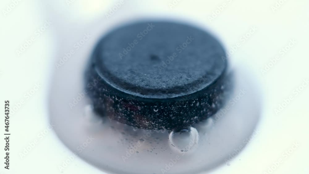 Close-up of a black tablet dissolving in water. Medical background in ...