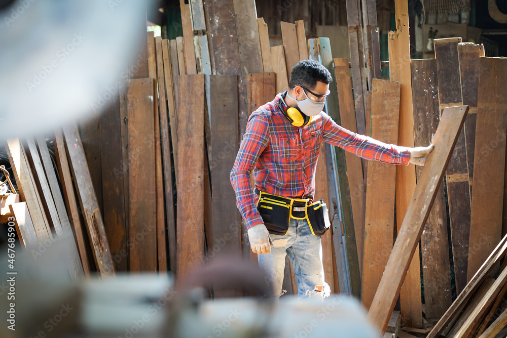 Yong Caucasian male carpenter in safety goggles, face mask, and ear ...