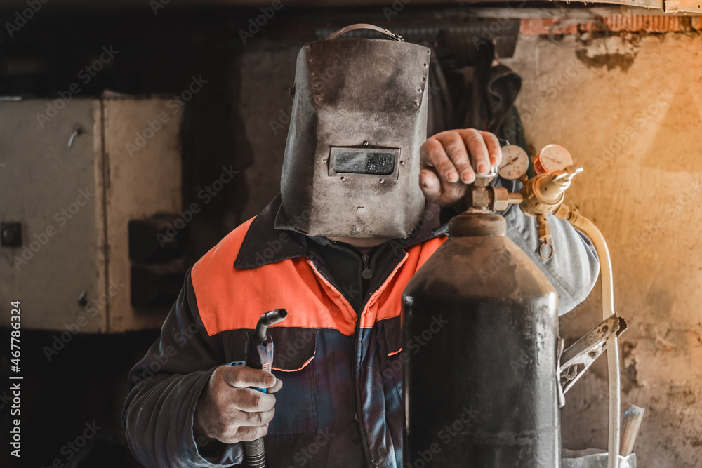 A man welder worker stands in front of a welding machine and a carbon ...