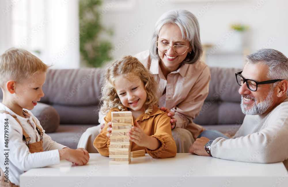 Excited children playing game Jenga at home with positive senior ...