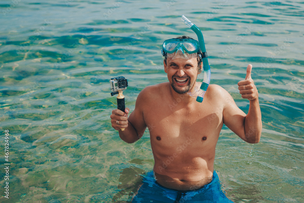 A man wearing a scuba diving mask against a clear blue sky and ...
