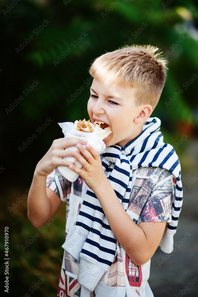 Cute blonde boy eating shrimp roll at fast food restaurant. Unhealthy ...