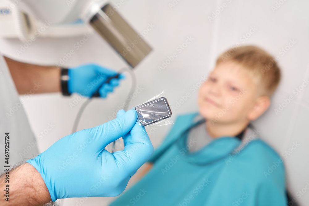 Doctor pointing X-ray unit holding electronic sensor in child. Dentist ...