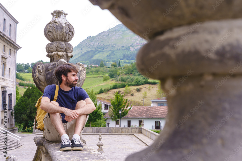 Panoramic view of spanish young man sit on stairway with a countryside ...