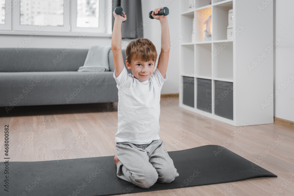 Portrait of boy child exercising with dumbbells at home. A child who ...