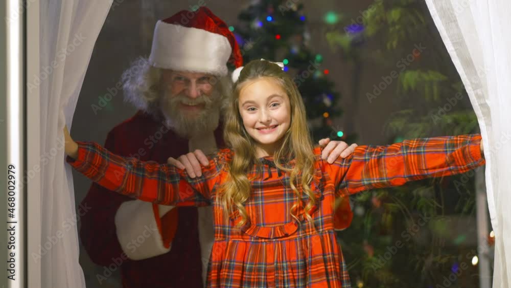 Excited little girl looking out the window as Santa Clause entering ...