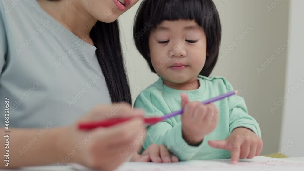 Mom teaching son how to painting with crayon color on book or doing ...