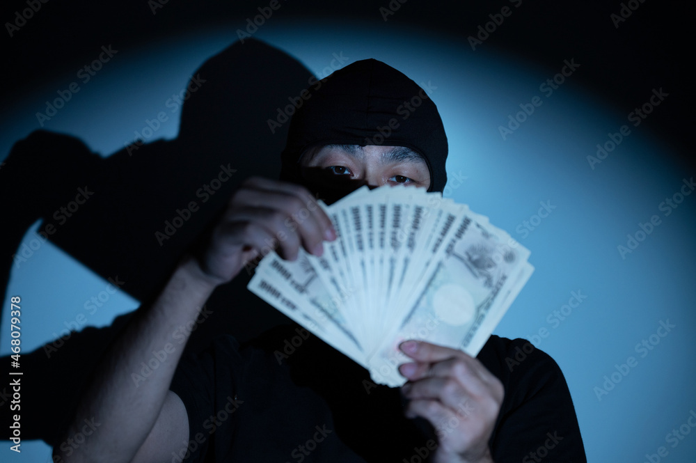 Fotka „Image of a bad robber counting wads of cash that could be used ...