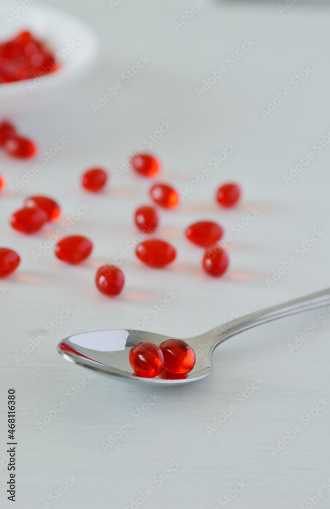 Couple of soft gel Gac oil or Momordica cochinchinensis oil on a spoon ...