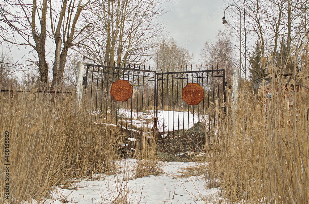 Closed metal gate with stop signs. Forgotten, abandoned ghost town ...