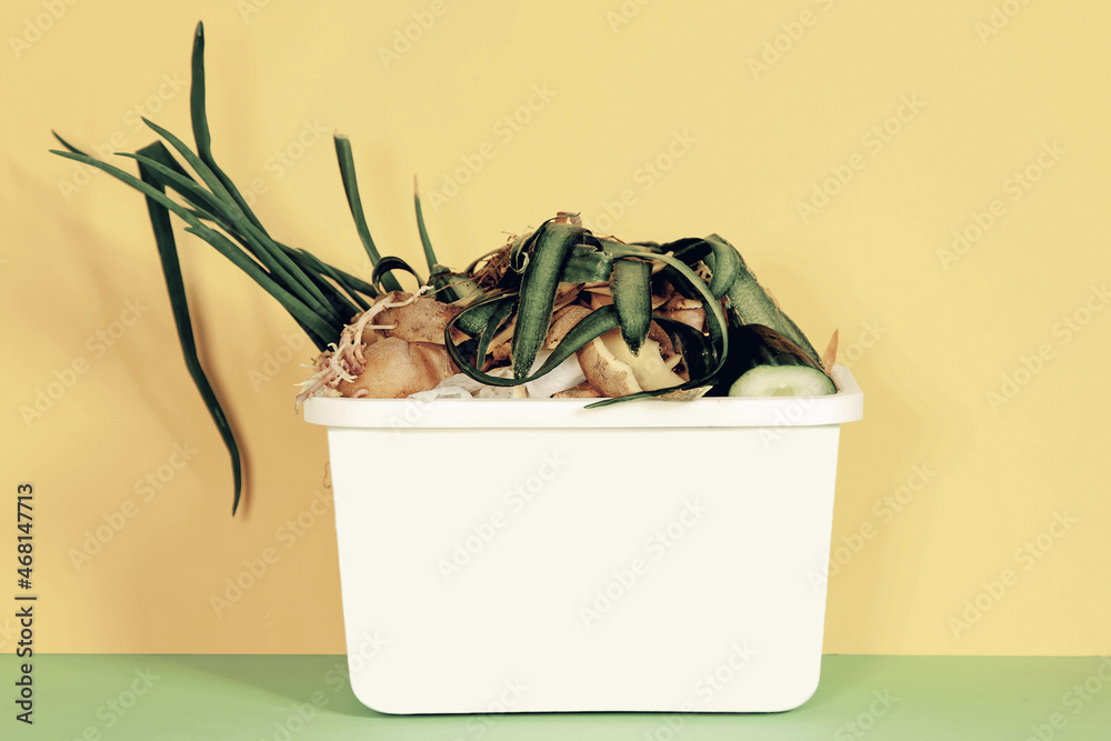 Kitchen composting bin. Peeled vegetables in white compost bin on multi ...