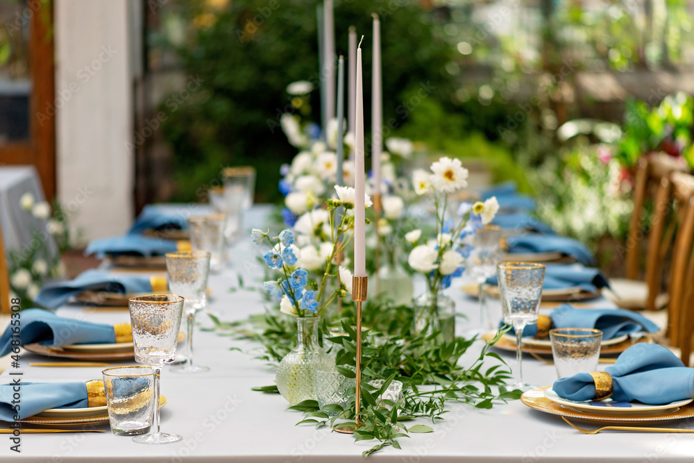Banquet wedding table setting with blue napkins, gold cutlery, crystal ...