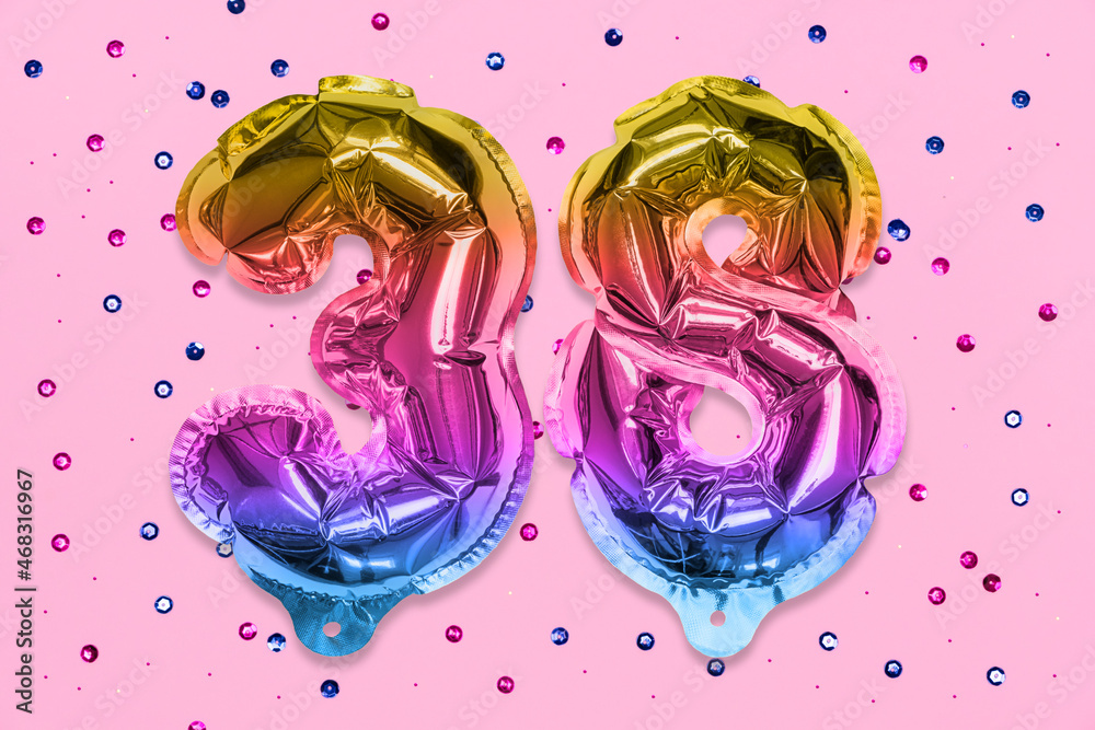 Rainbow foil balloon number, digit thirty eight on a pink background ...