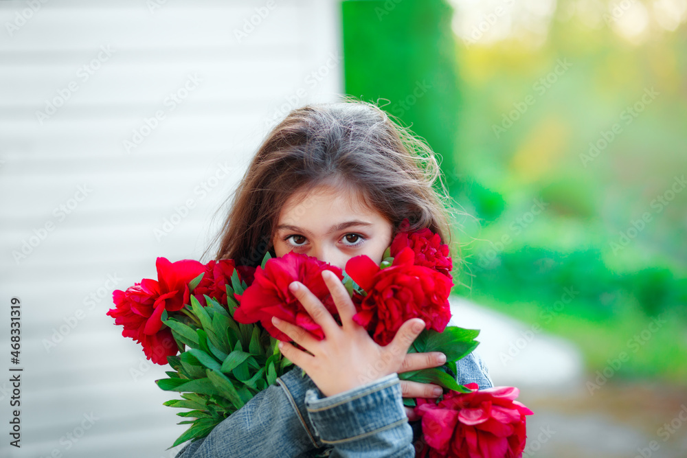 Little cute girl with peony flowers. Child playing in summer garden ...