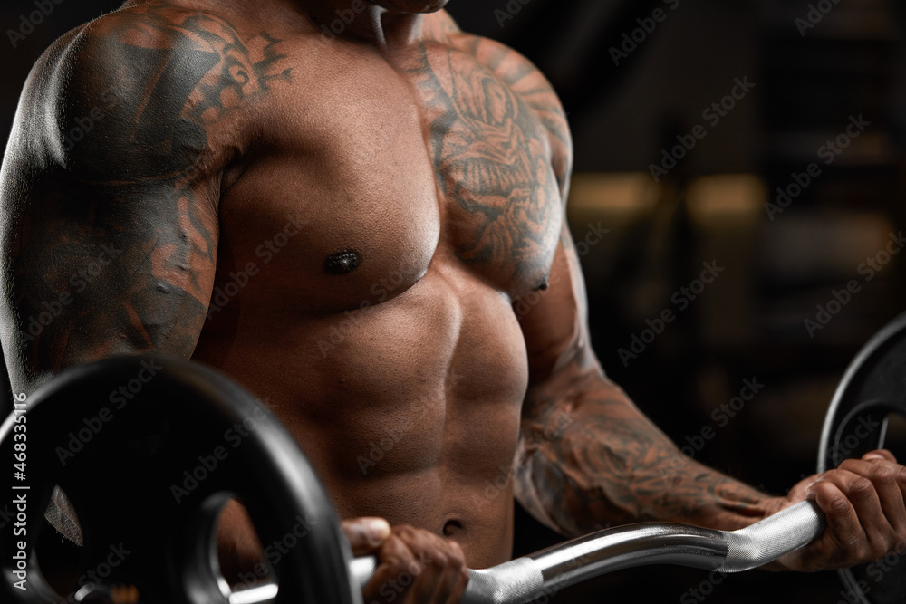 Strong and muscular dark skin man trains on modern equipment in gym ...