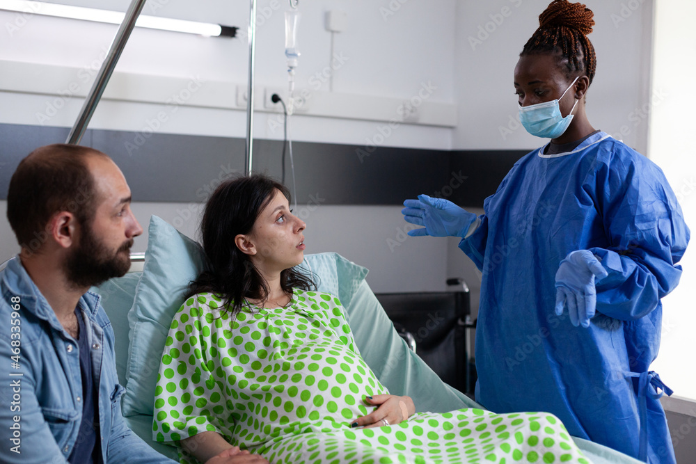 Woman with pregnancy talking to obstetrics nurse while sitting in ...