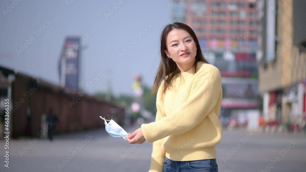 Young pretty Chinese Asian woman takes off the face mask breathes fresh ...