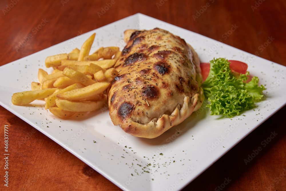 pizza calzone, un plato de calzone acompañado de vegetales y papas a la ...