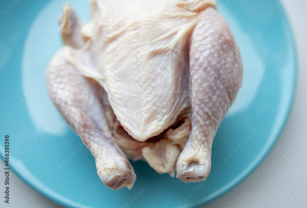 broiler chicken carcass, with skin, on a plate, on a light background ...
