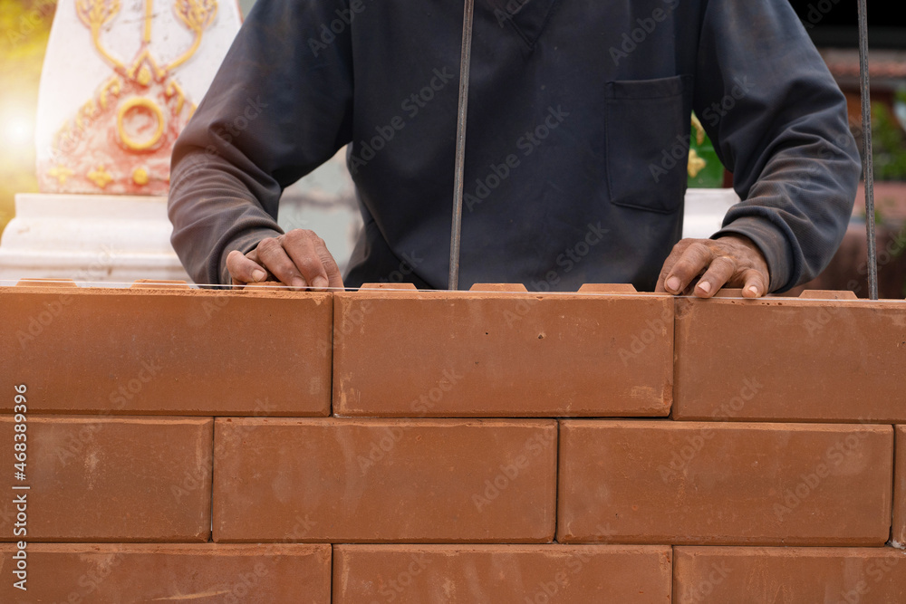 Builder carefully puts red brick on the masonry. Quick work bricklayer ...