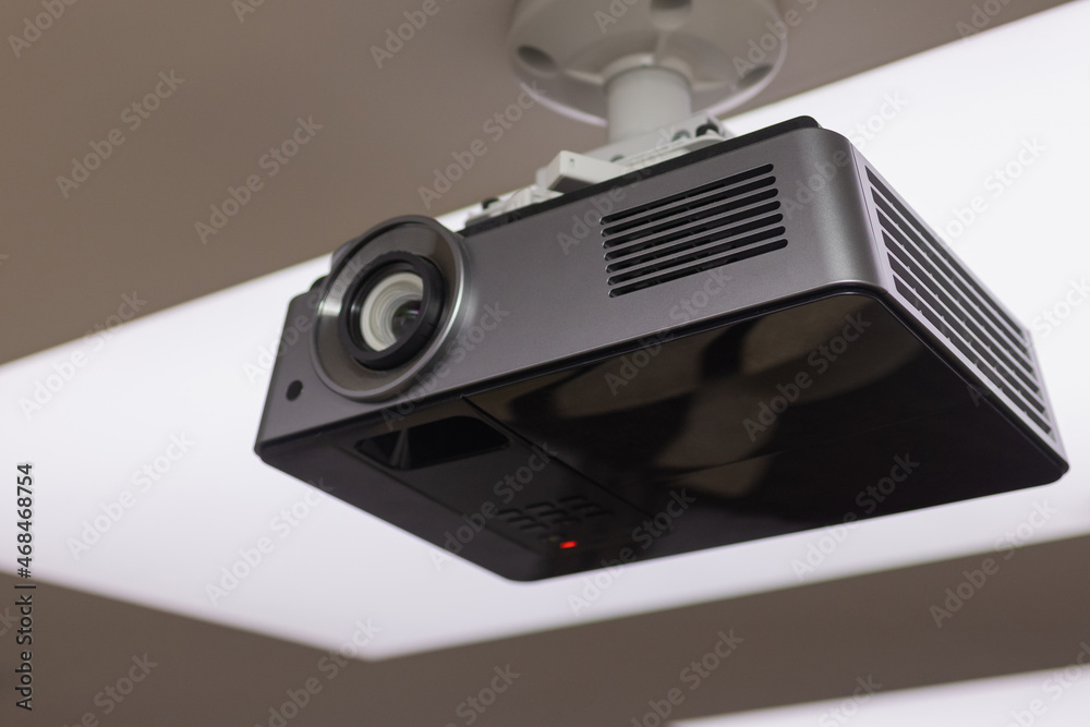 A black overhead projector on ceiling in a conference room modern ...