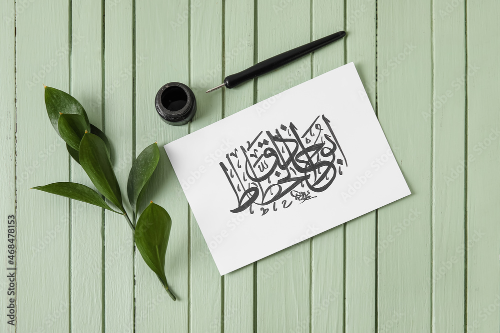 Paper with Arabic text and tools for calligraphy on wooden background ...