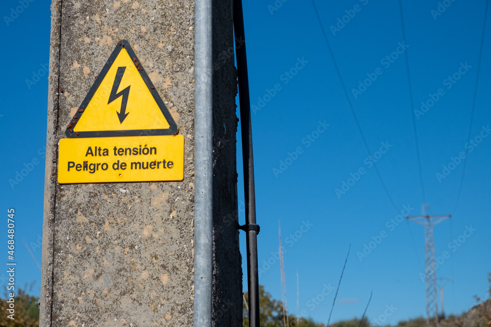 Concrete pole of a high voltage power line, with the warning sign that ...