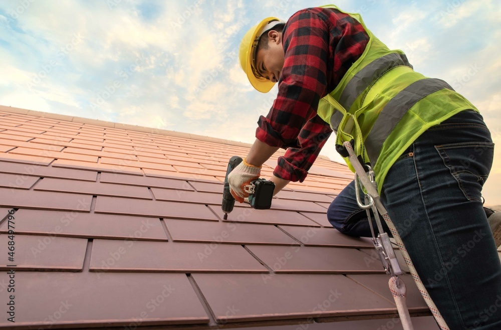 Roofer working in special protective work wear gloves, using air or ...