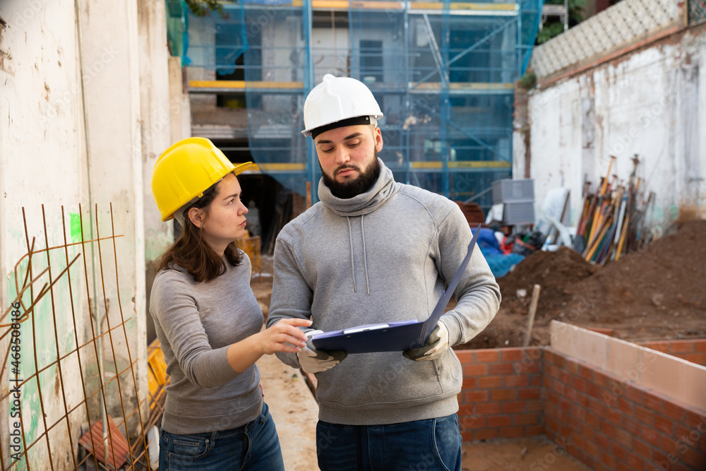 Civil engineers inspecting process of building overhaul, comparing to ...