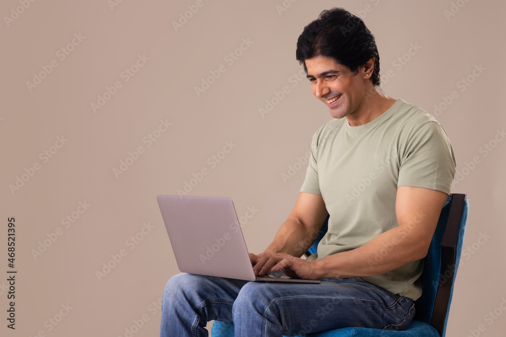 Indian man using laptop on his lap while sitting on chair Stock Photo ...